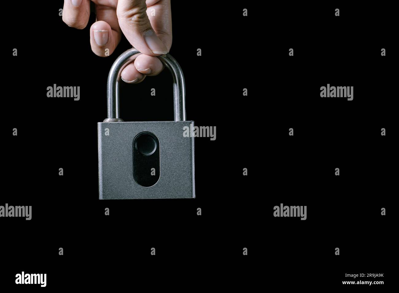 A hand is holding a fingerprint padlock. Isolated black background ...