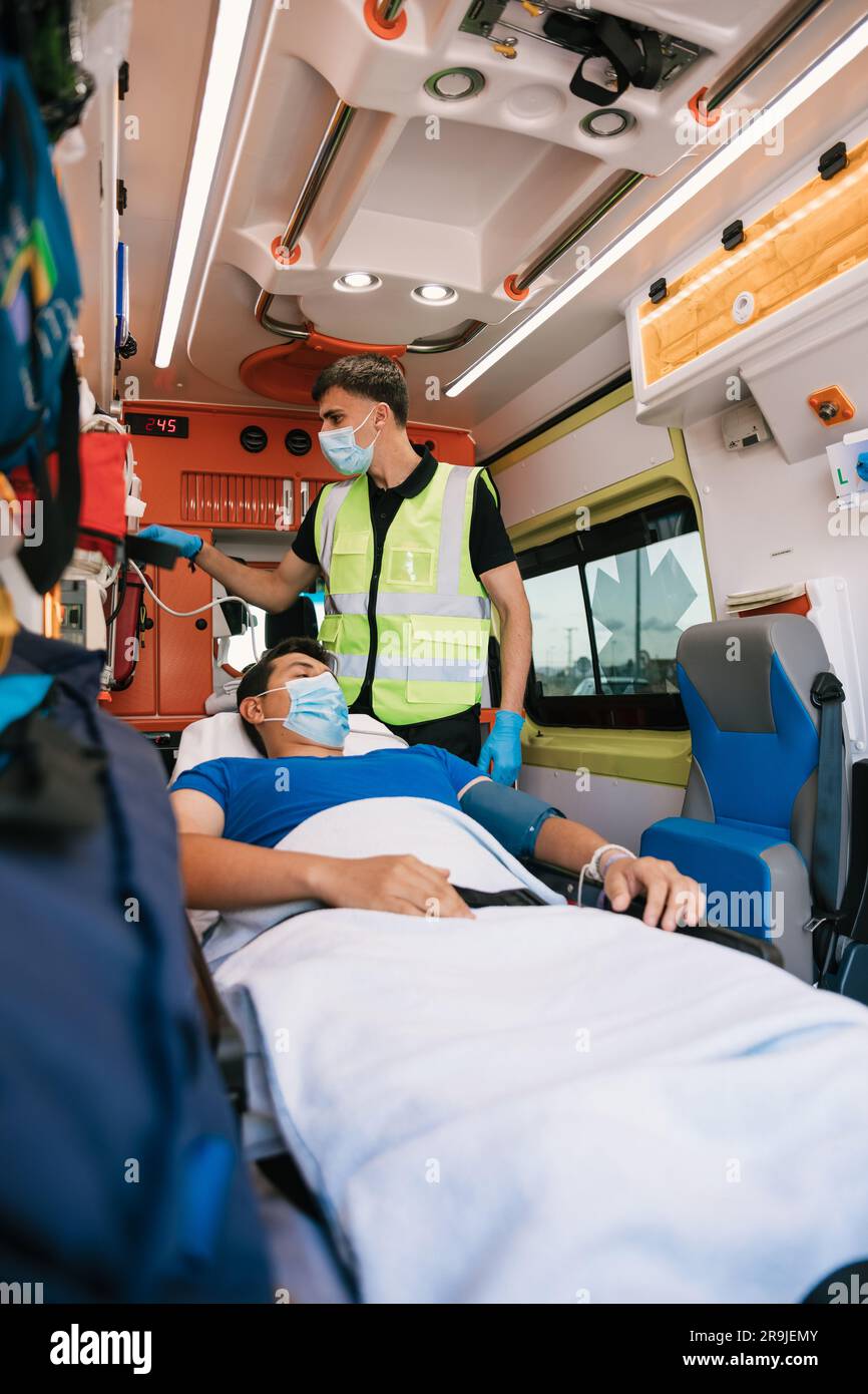 Side view of specialist connecting equipment to patient lying on ...