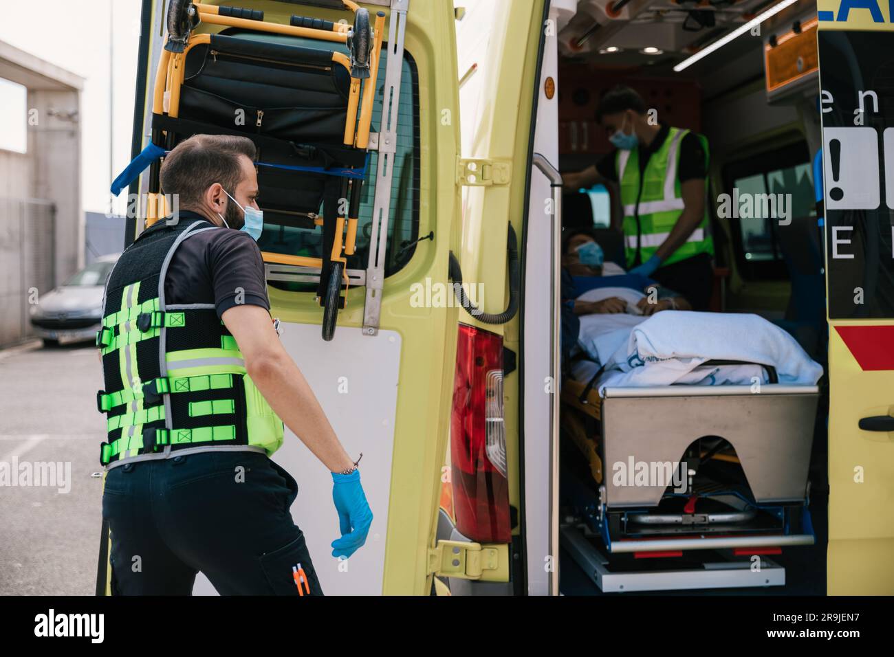 Side view of ambulance employee in uniform standing against car with ...