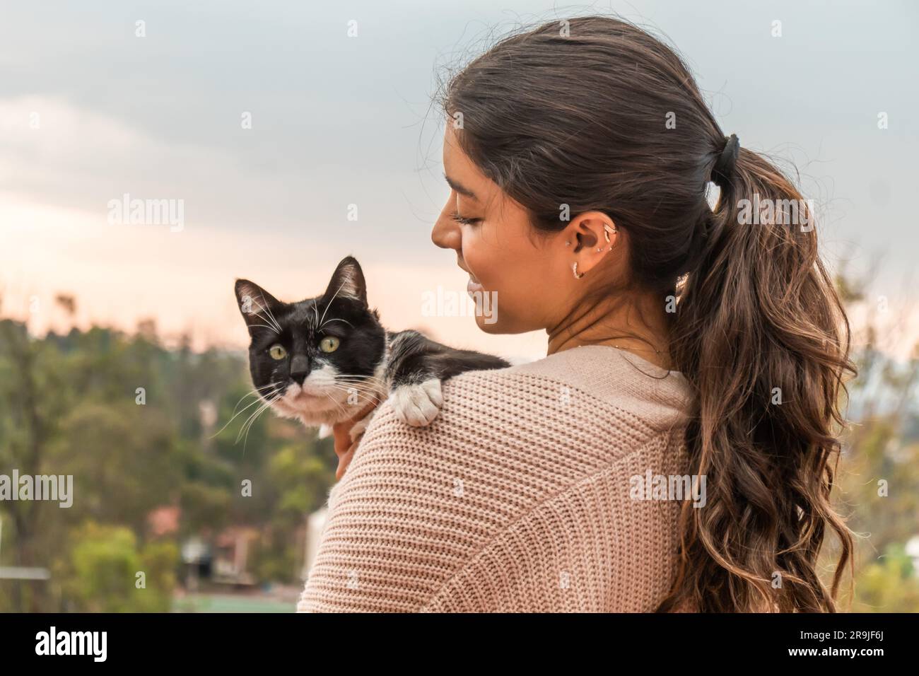 Back view of happy female owner hugging cute adopted white and black ...