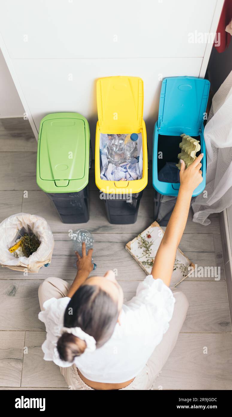 Top view of young woman sitting on floor while recycling cardboard at ...