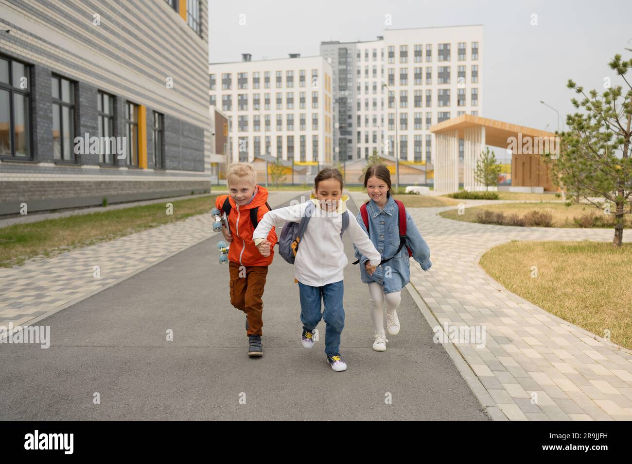 Cheerful children in cozy casual clothes with backpacks running with ...