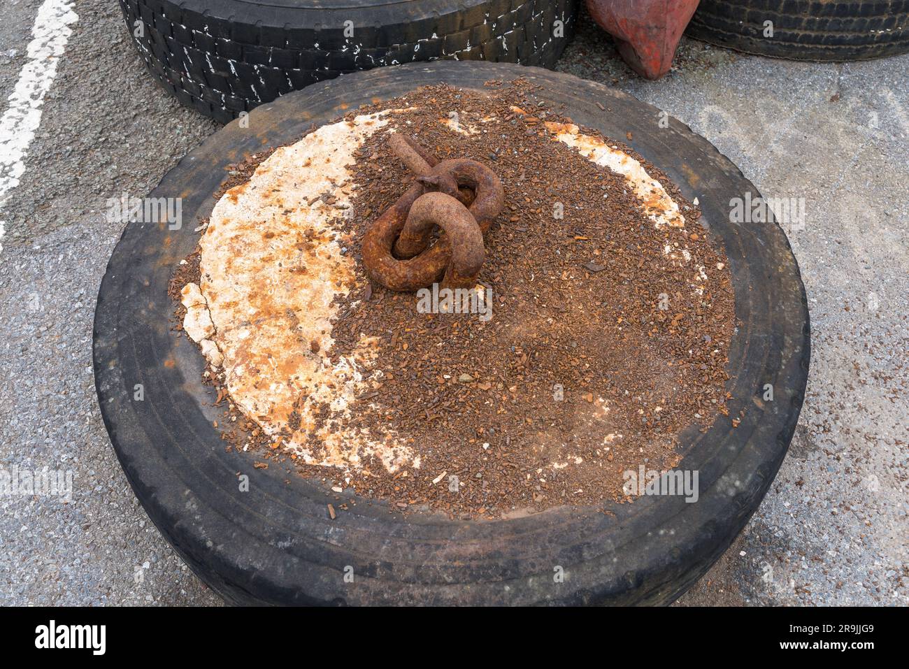 Old tyres filled with concrete with rusty chain attached for holding ...