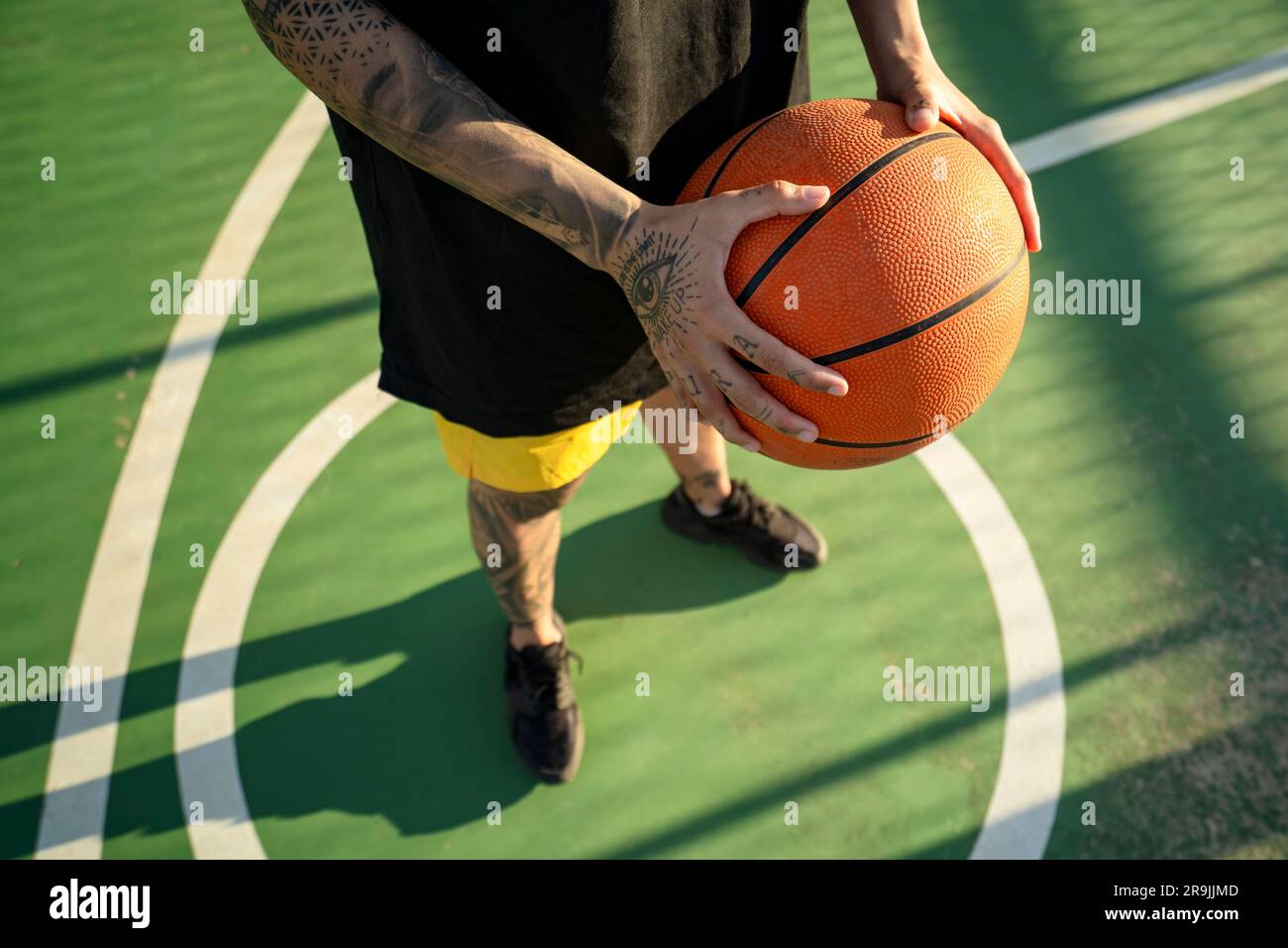 From above crop anonymous basketball player with tattoos holding ball ...