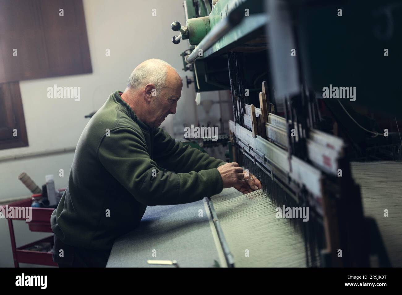 Side view of concentrated senior male working standing at workbench and ...