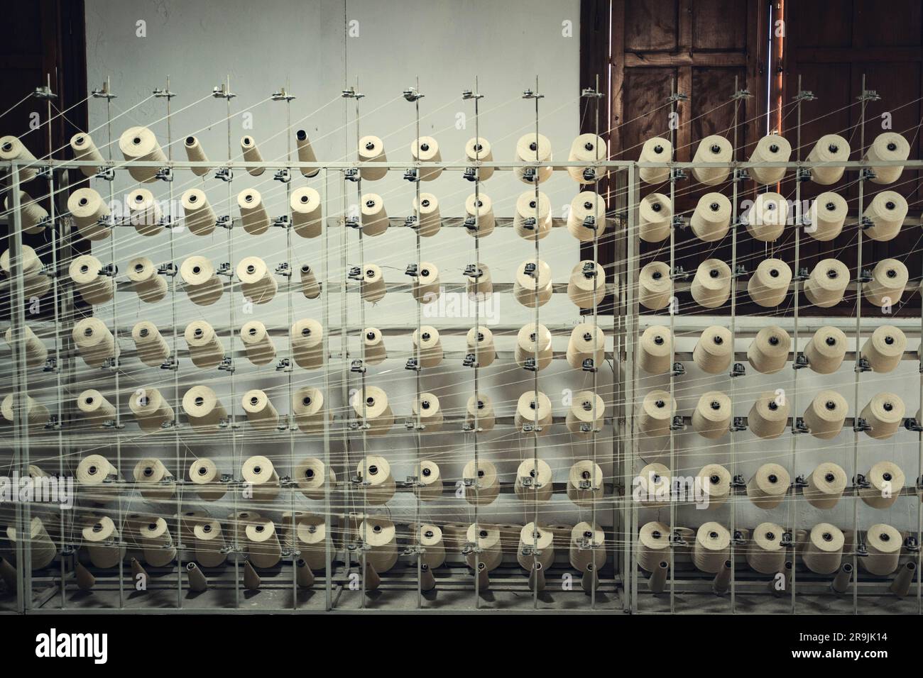 Rows of white thread hanging on metal stand in cotton mill factory ...
