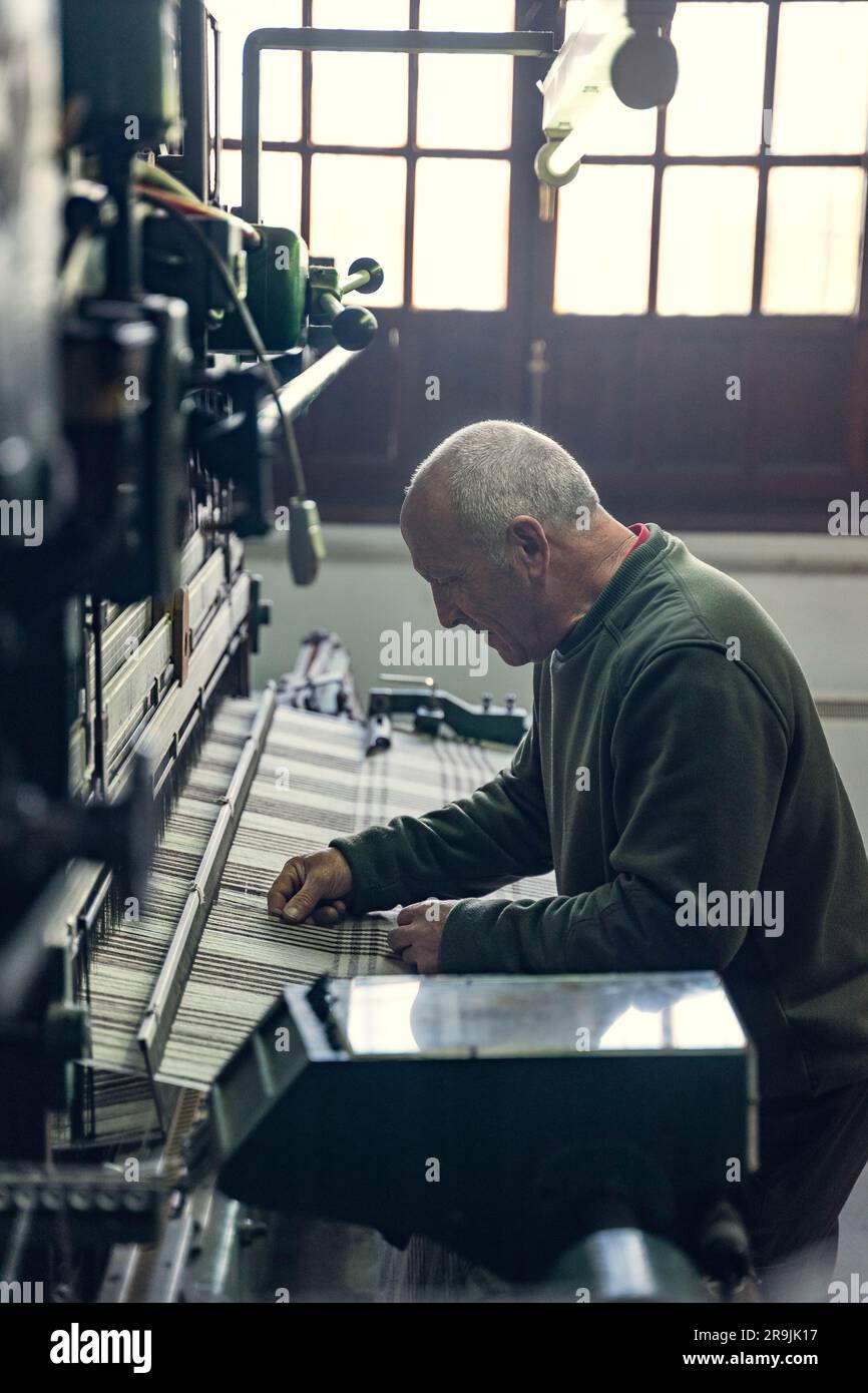 Side view of concentrated senior male worker standing at workbench and ...