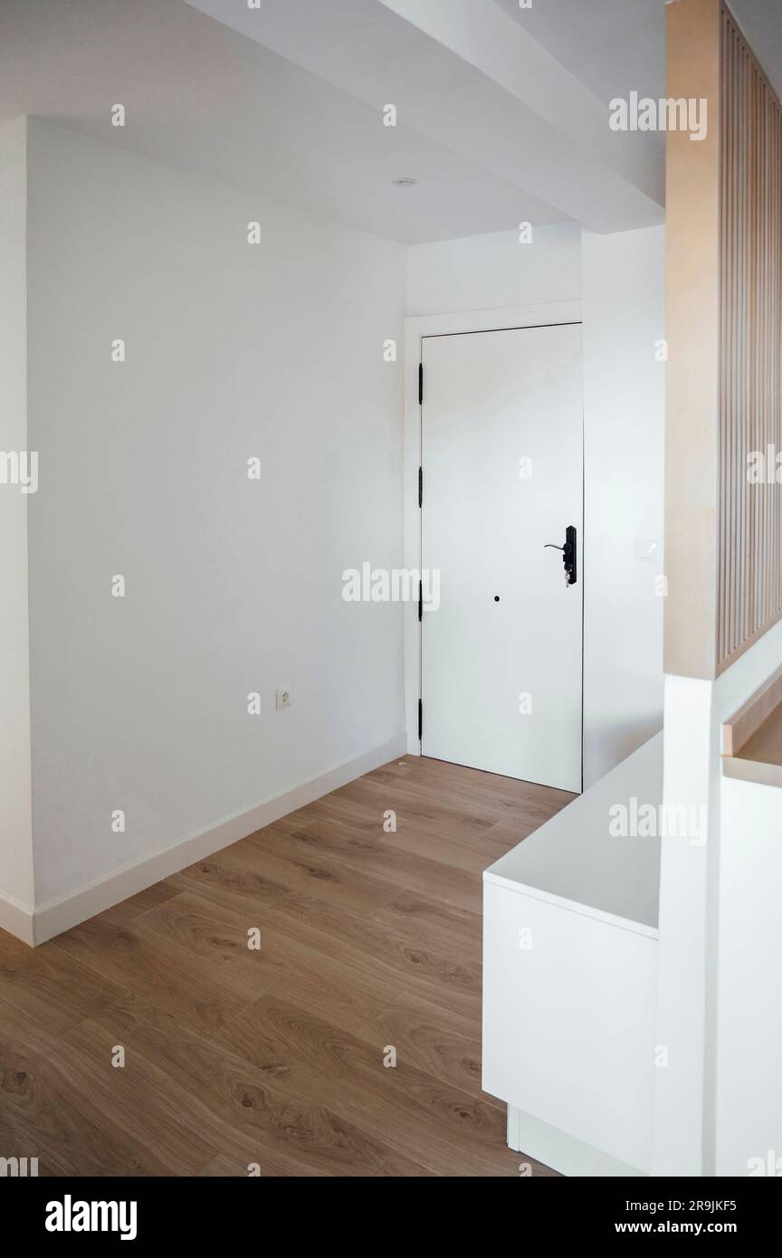 Interior design of narrow light room with white walls and closed door ...