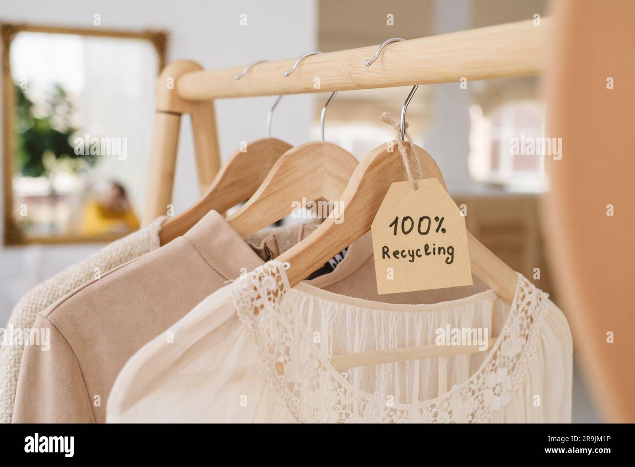 Beige clothes on hangers hanging on wooden rack with paper tag with 100 ...