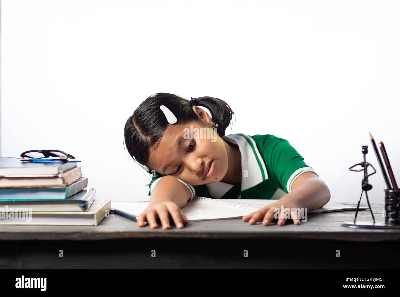 A pretty beautiful Indian schoolgirl child lying exhausted on study ...