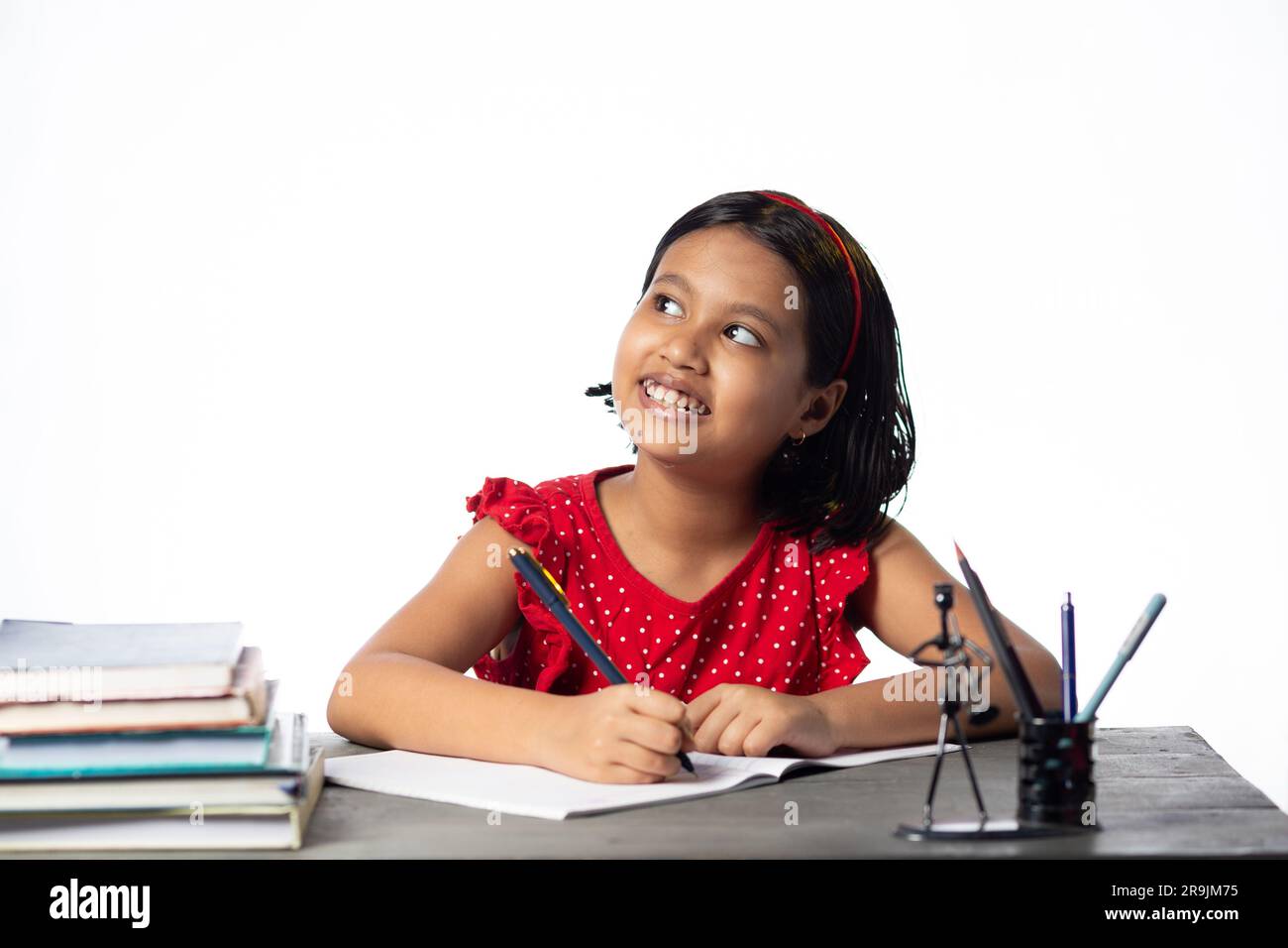 A pretty beautiful Indian girl child studying and looking upwards at ...