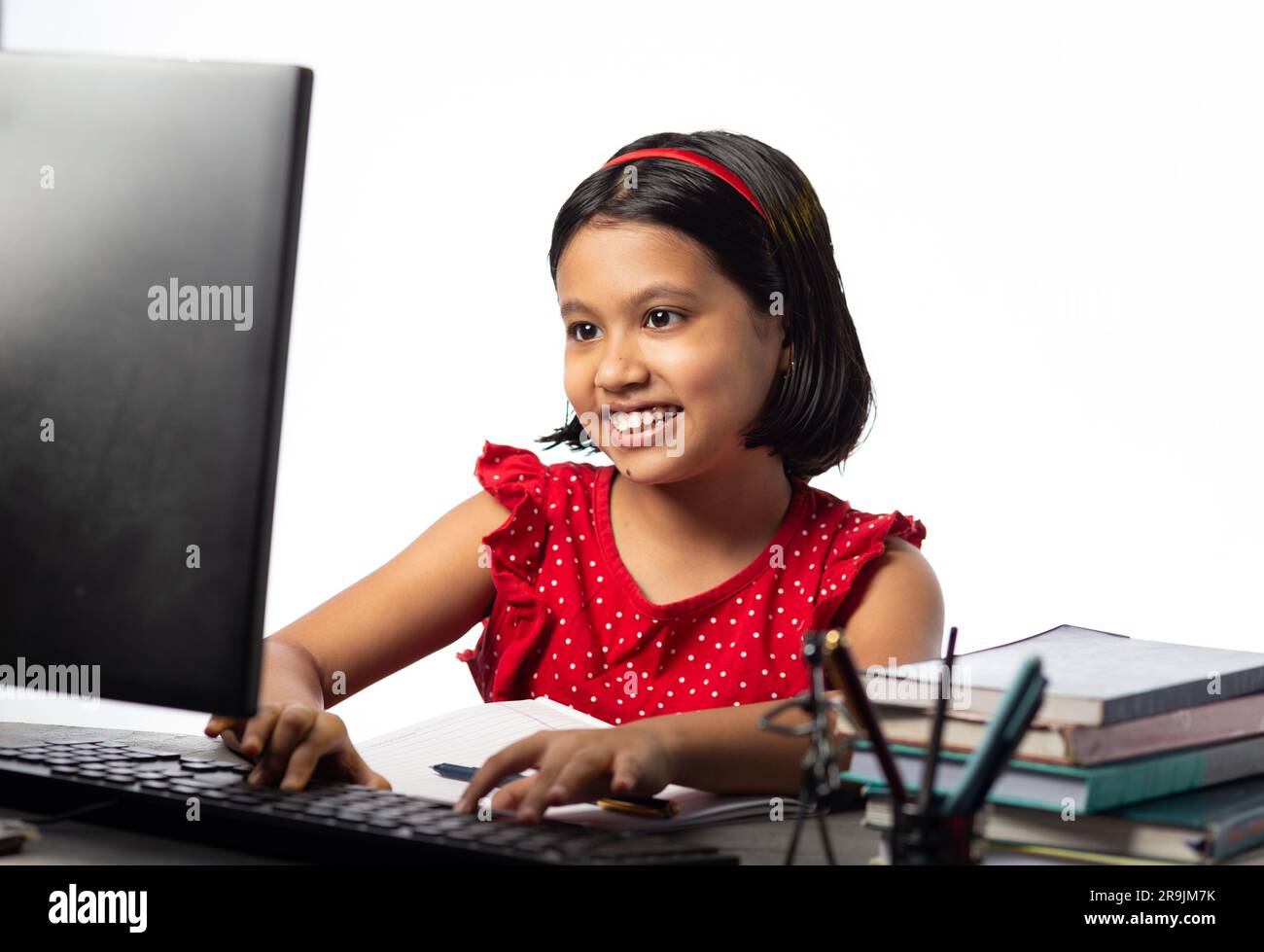 A pretty beautiful Indian girl child studying with desktop computer at ...