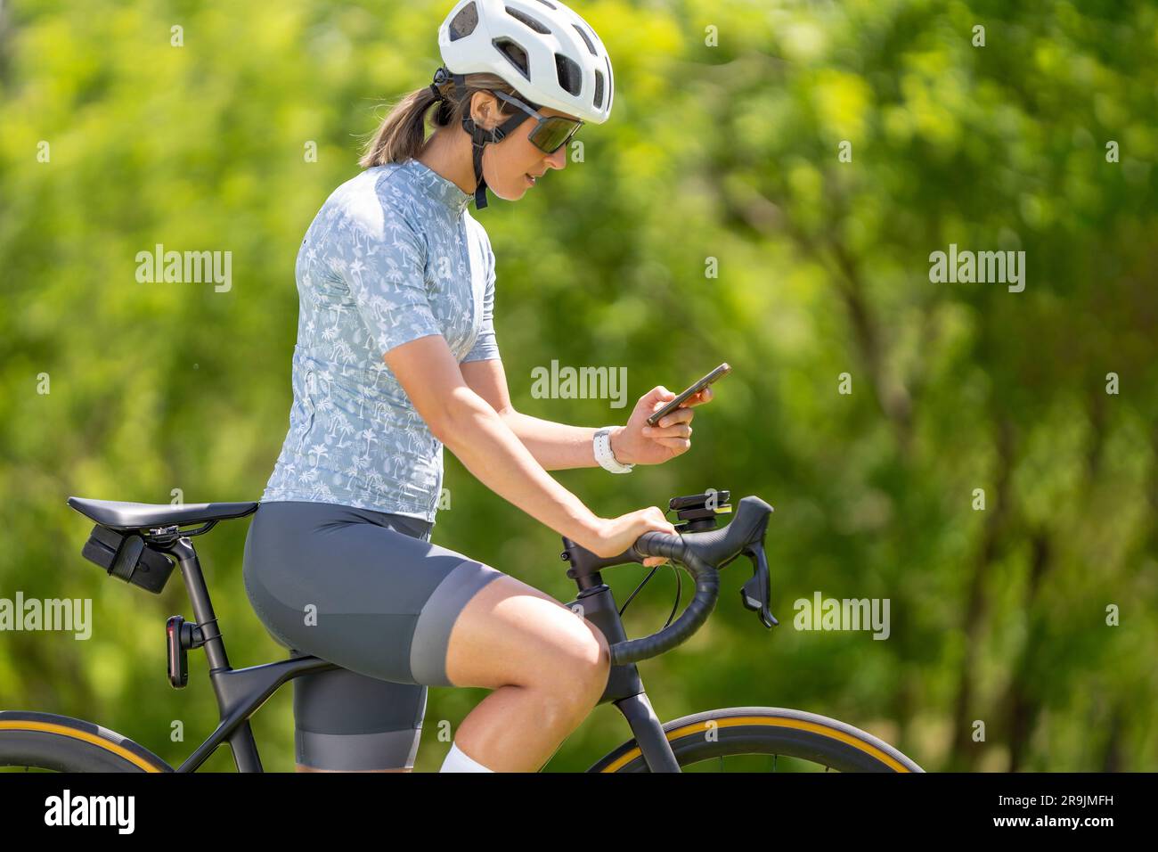 Side view of fit female cyclist in helmet and sunglasses in sportswear ...