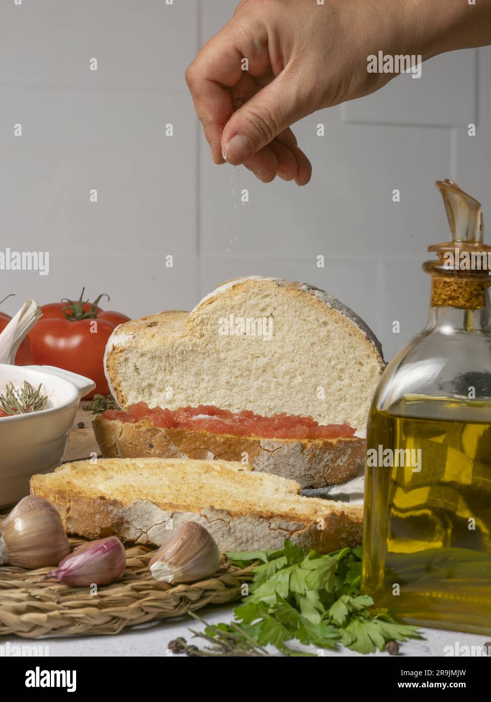 Crop hand of anonymous cook sprinkling salt on bread with tomato spread ...