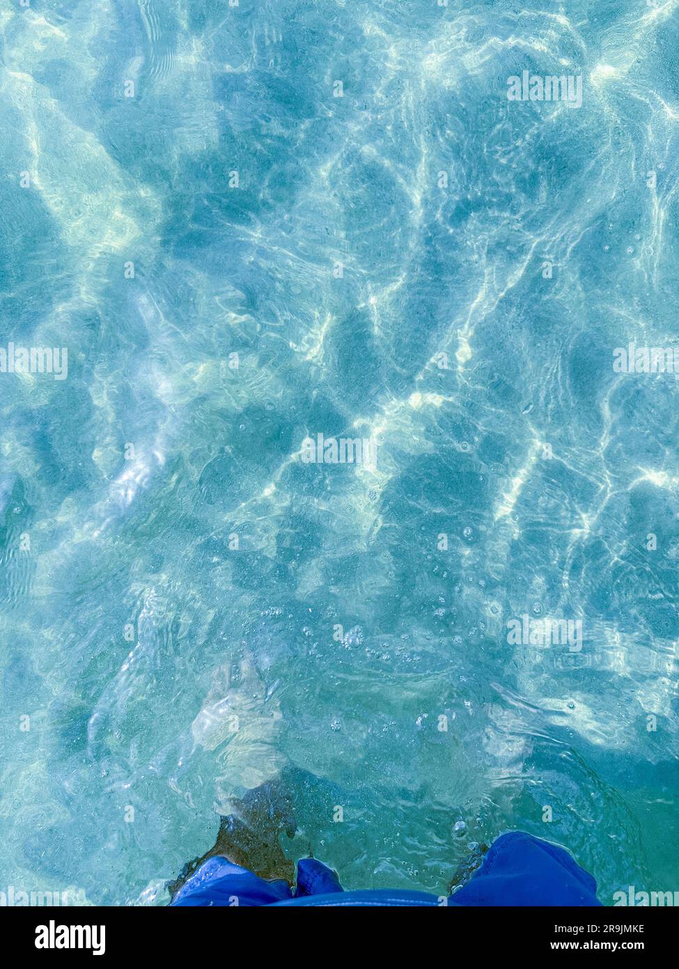 Feet in shallow blue water Stock Photo - Alamy