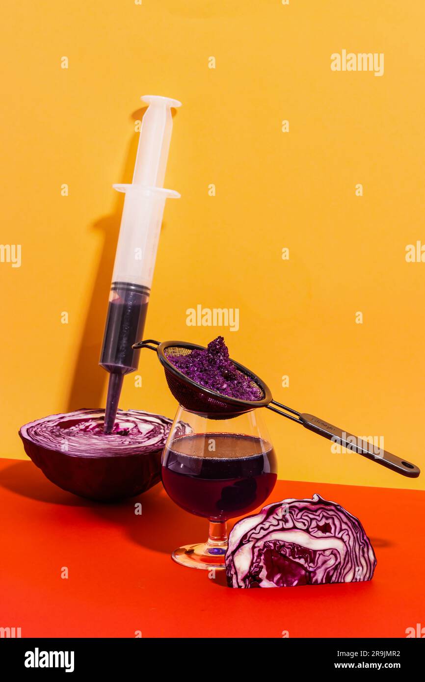 Composition of glass with strainer and syringe filled with homemade ...