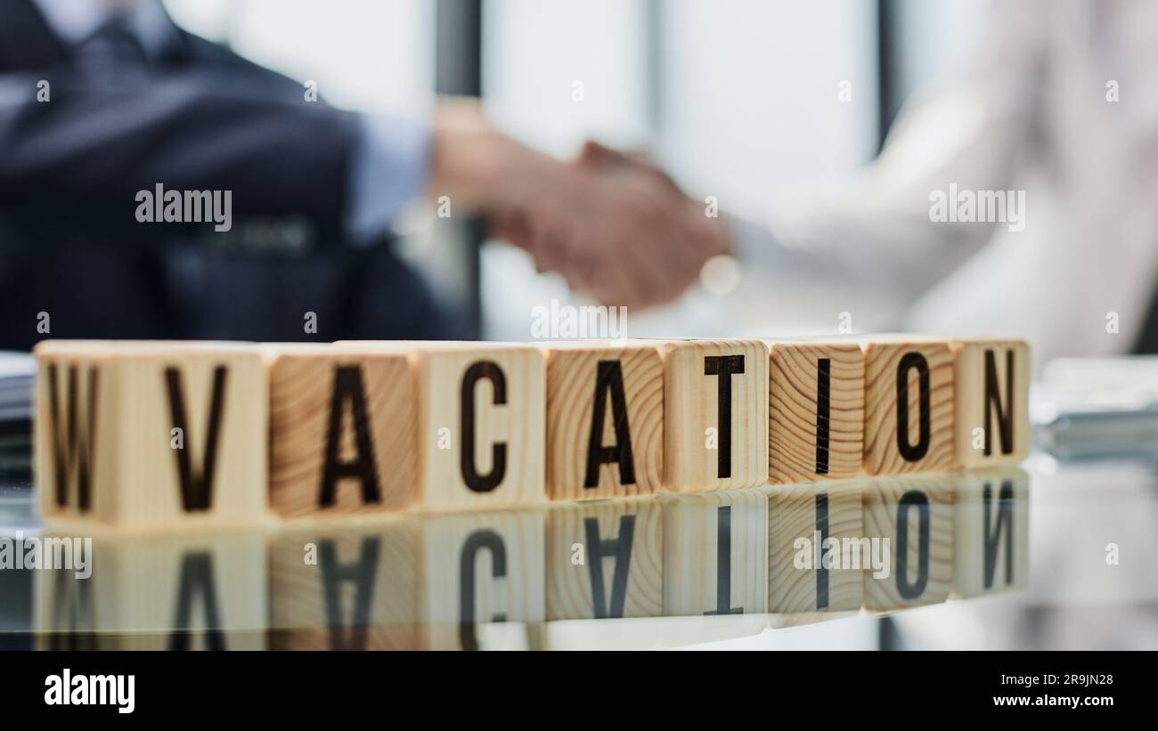 word vacation written with small wooden alphabet cubes on businessman ...
