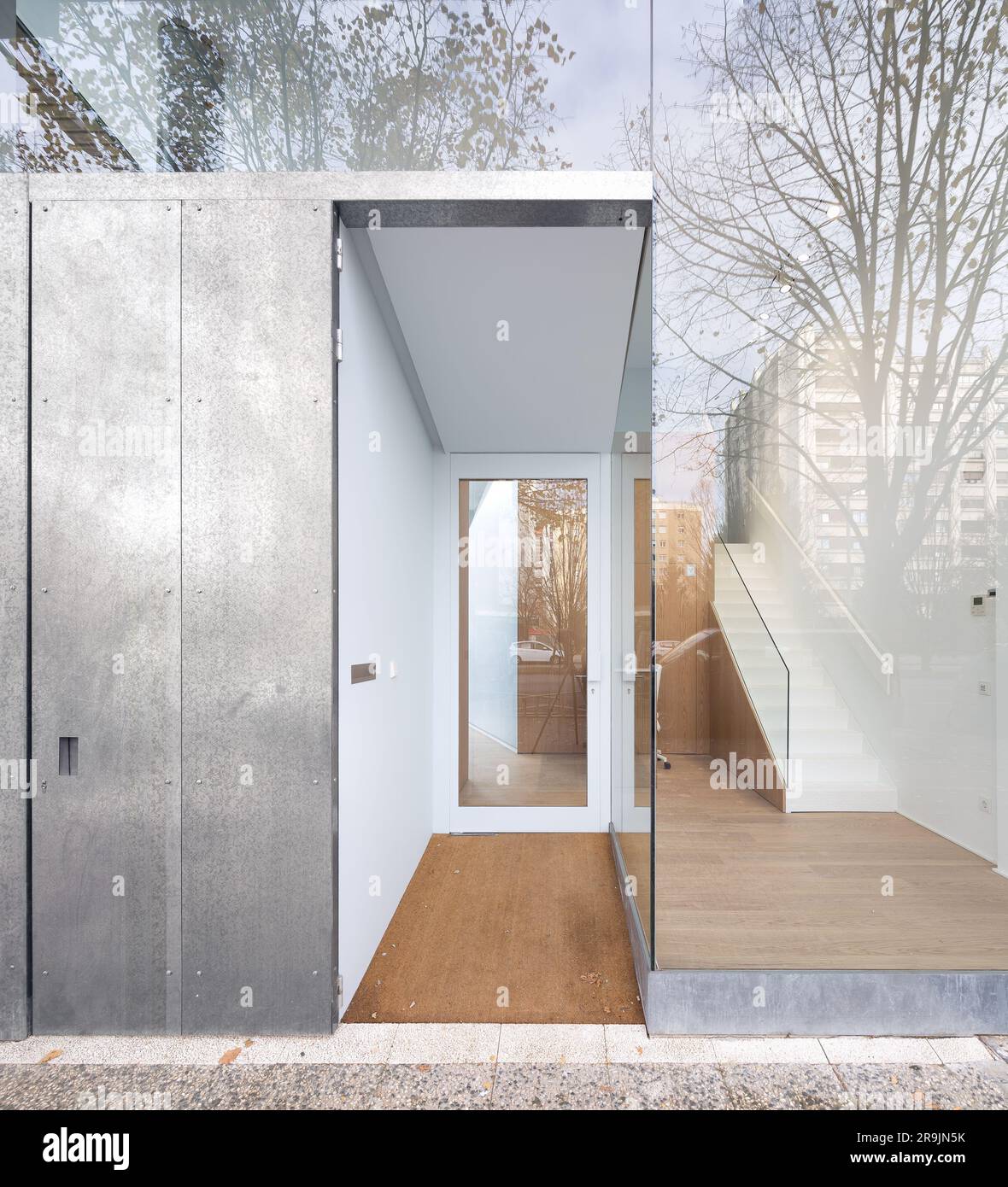 Modern building with open door and white walls with reflection of trees ...