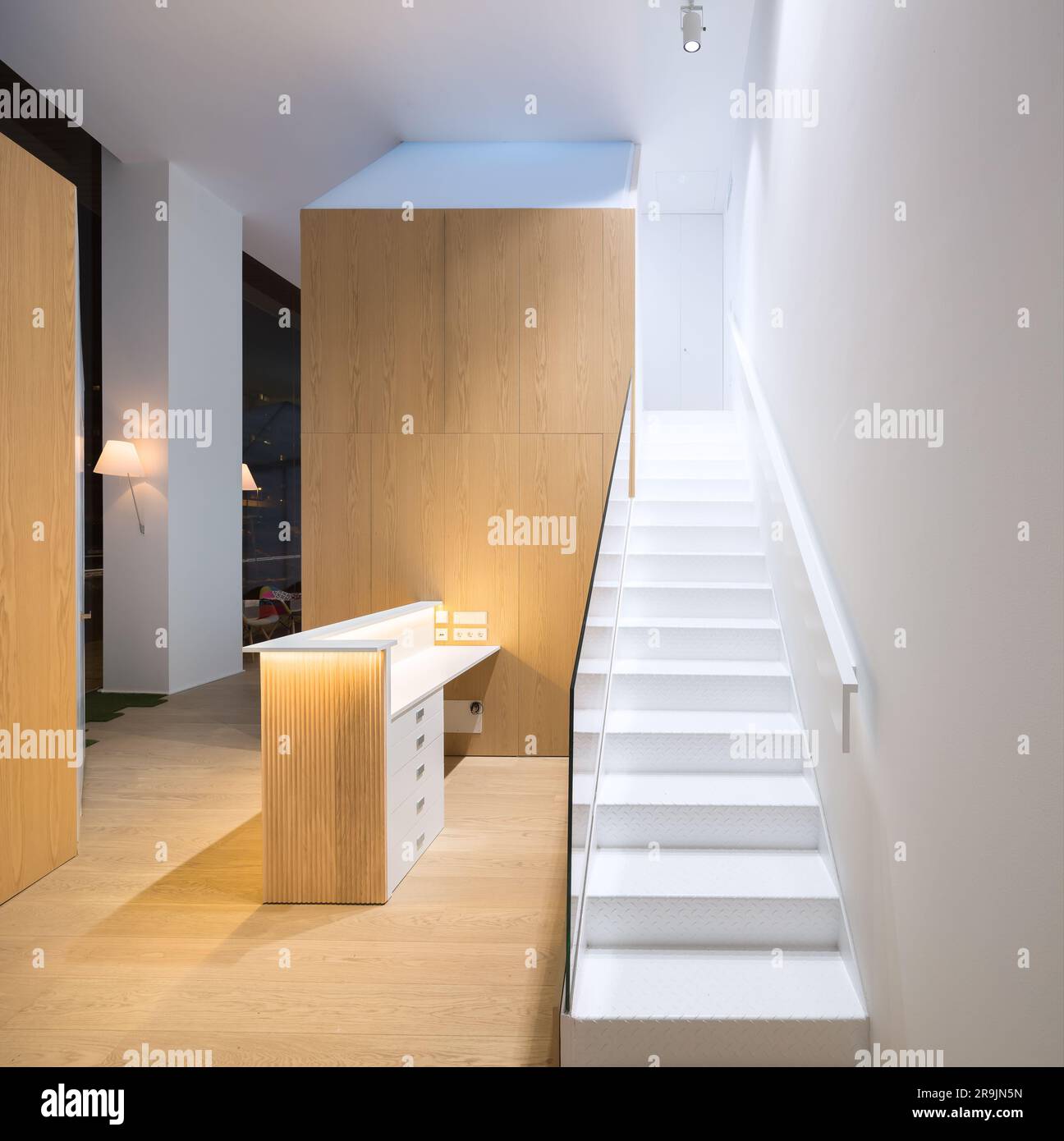 Interior design of illuminated reception desk near white staircase and ...