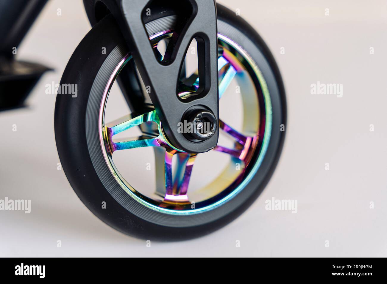 The front wheel of a rainbow-colored stunt scooter or a durable ...