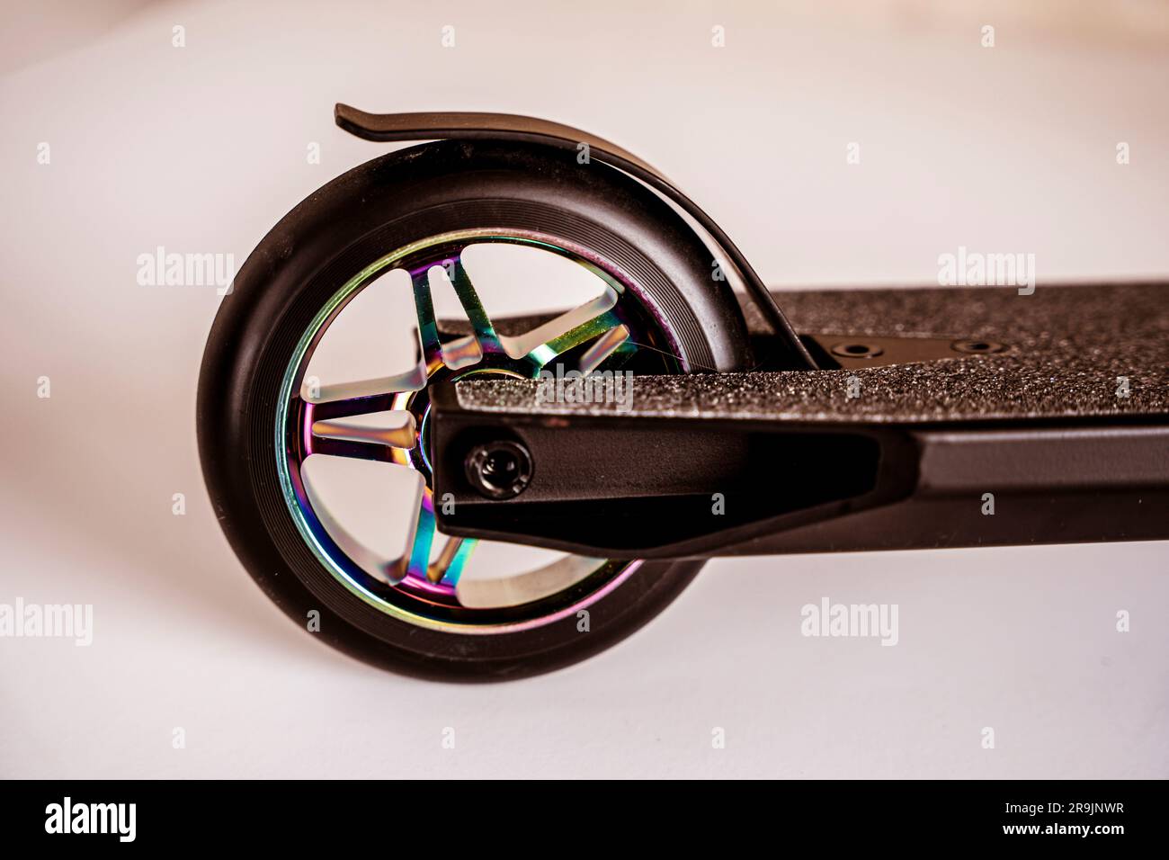 The rear wheel and brake of a Stunt scooter with rainbow-colored wheels ...