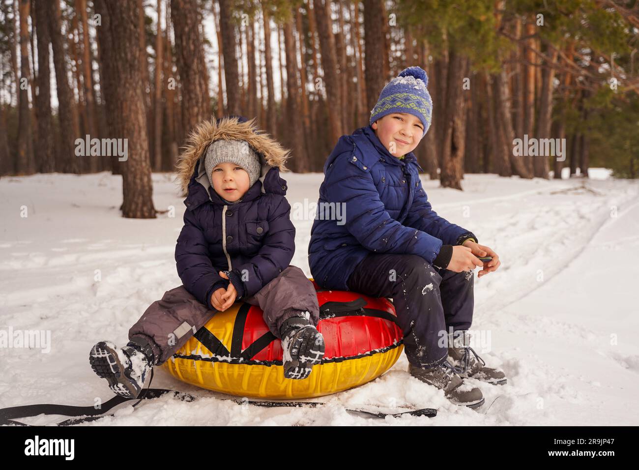Children sit on tubing in the snowy forest and take a break from the ...