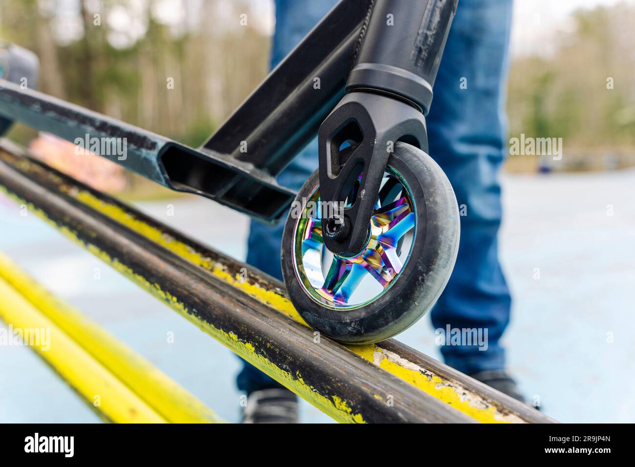 Rider boy legs close up in sneakers on stunt scooter on the skate park ...