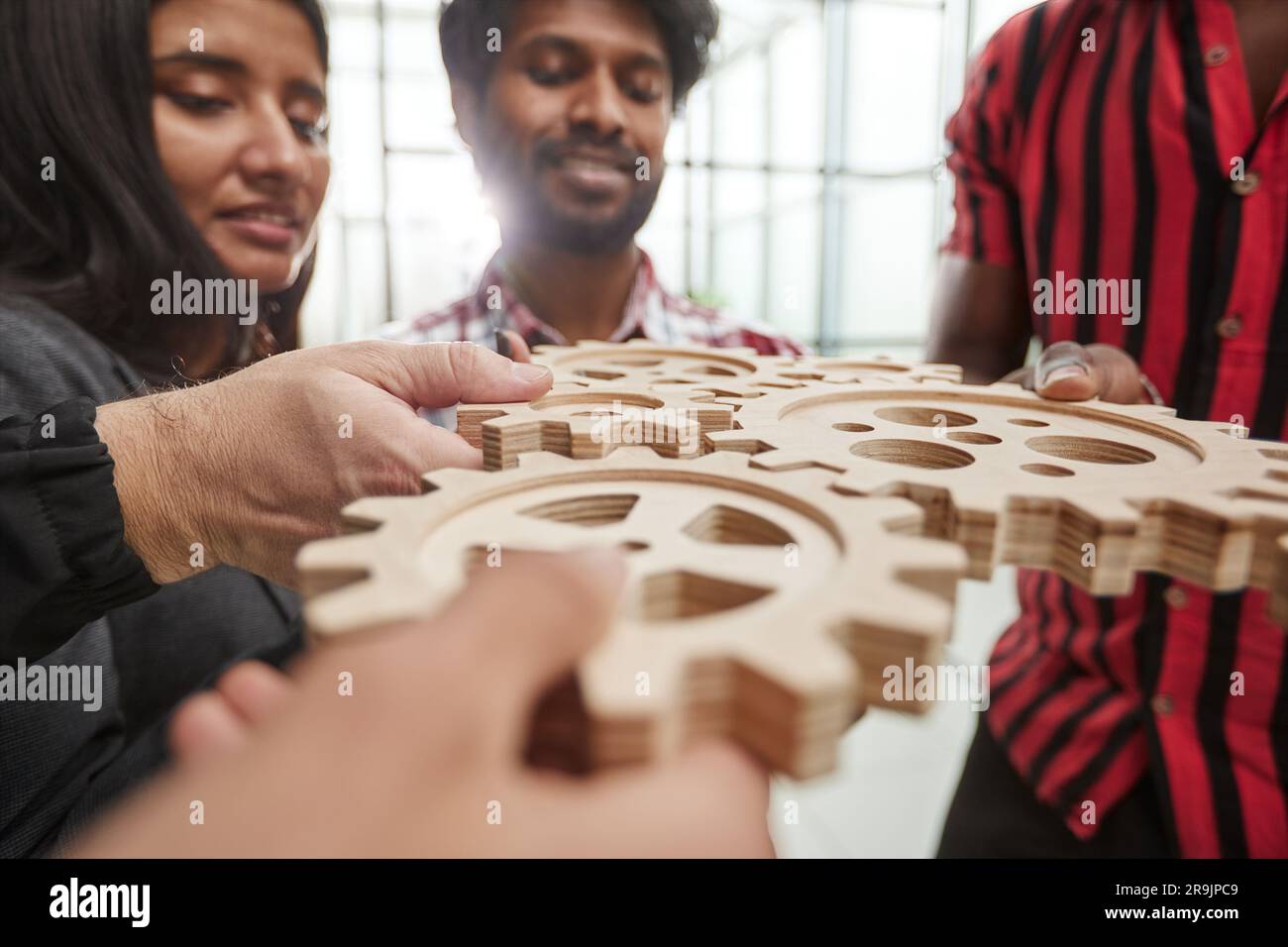 Office worker holding cog wheel as unity and teamwork in corporate ...