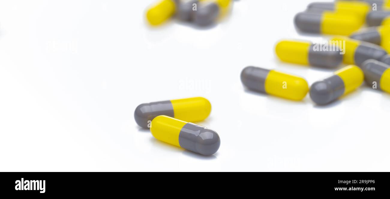 Closeup yellow and gray capsule pills on white background. Prescription ...