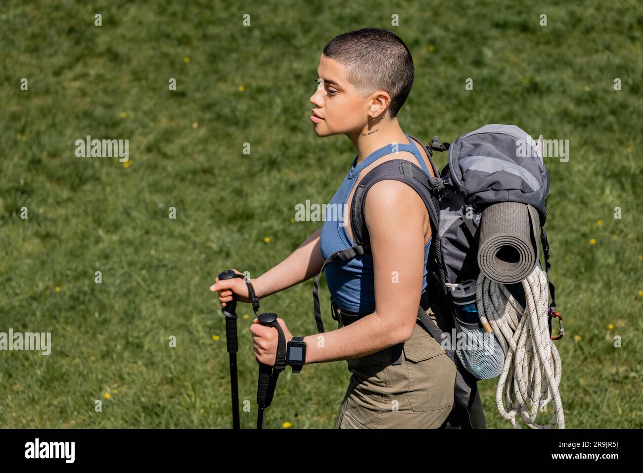 Young short haired and tattooed female hiker with backpack and fitness ...