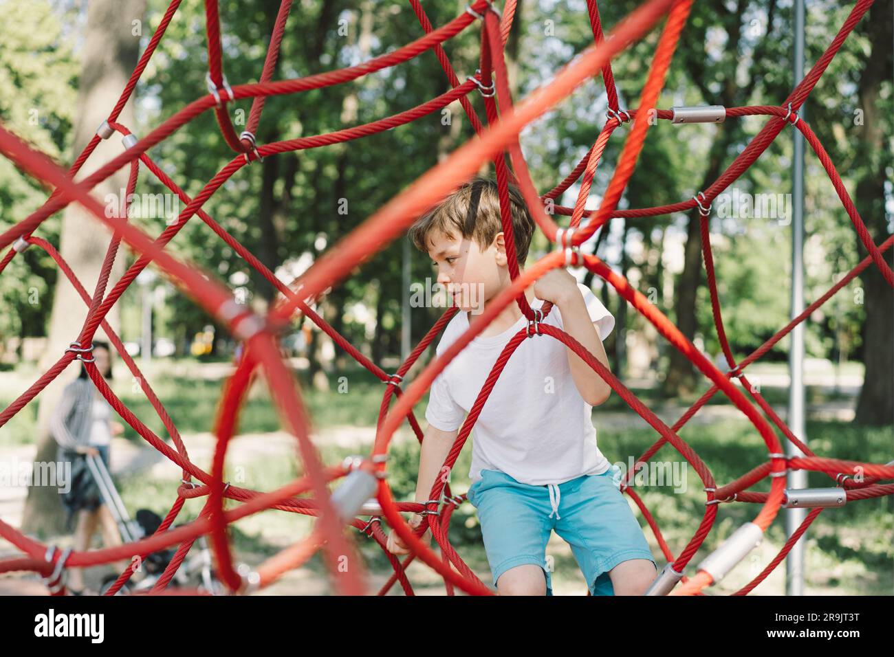 Happy boy child playing in rope spider web at playground Stock Photo ...