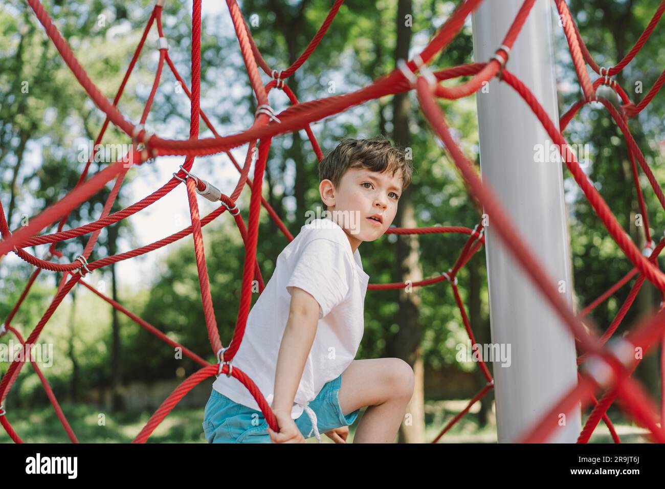 Happy boy child playing in rope spider web at playground Stock Photo ...