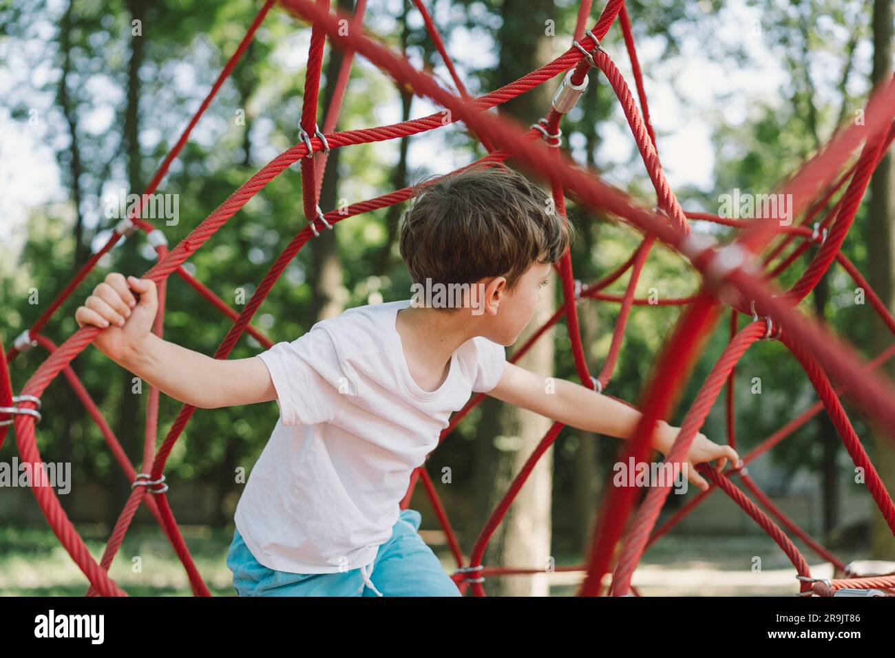 Happy boy child playing in rope spider web at playground Stock Photo ...