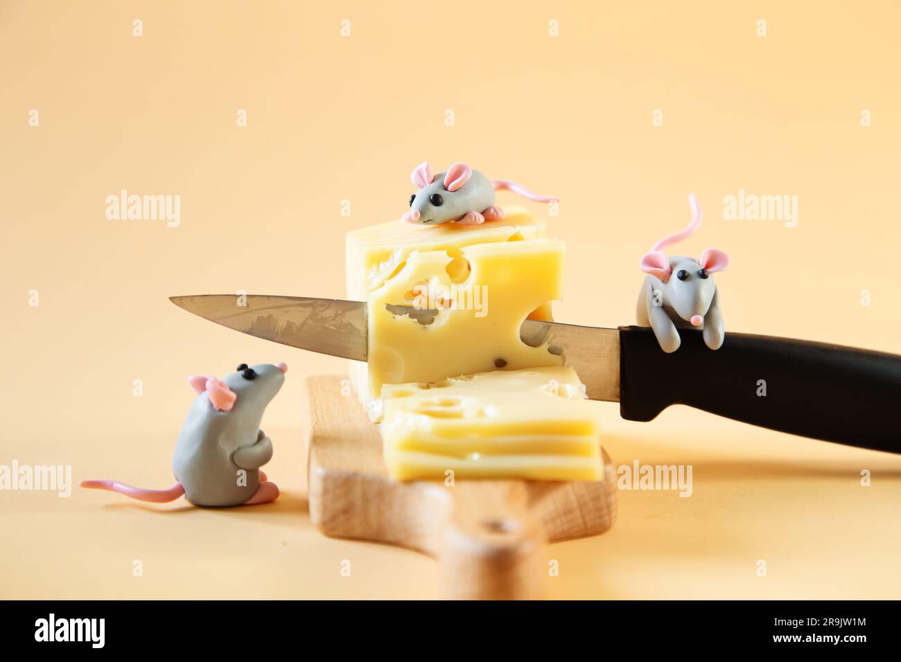 Little plasticine gray mice cut a piece of cheese. Beige background ...