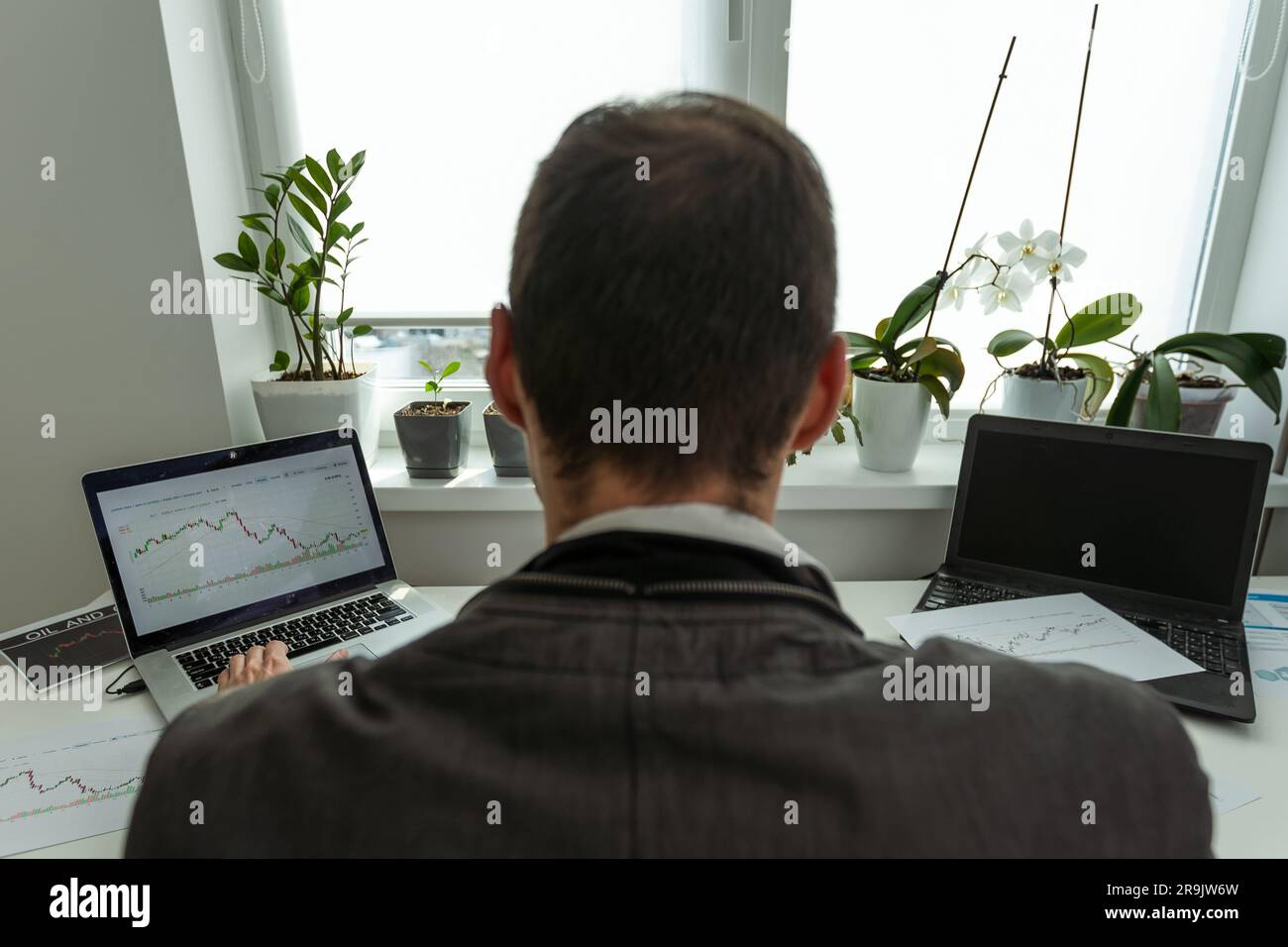 Back view of stock trader with raised hands looking at multiple computer screens with data and ...