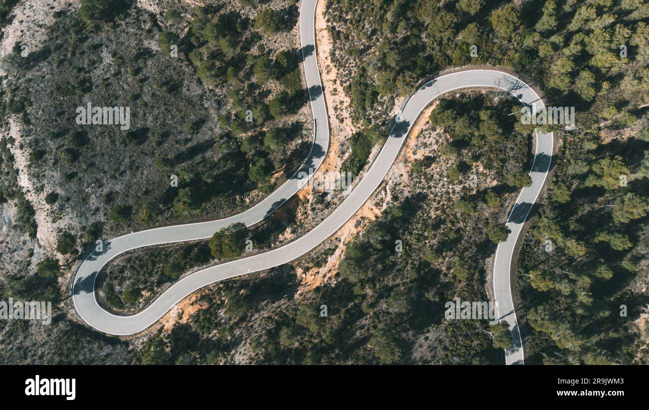 An Aerial view of a winding mountain road surrounded by lush greenery ...
