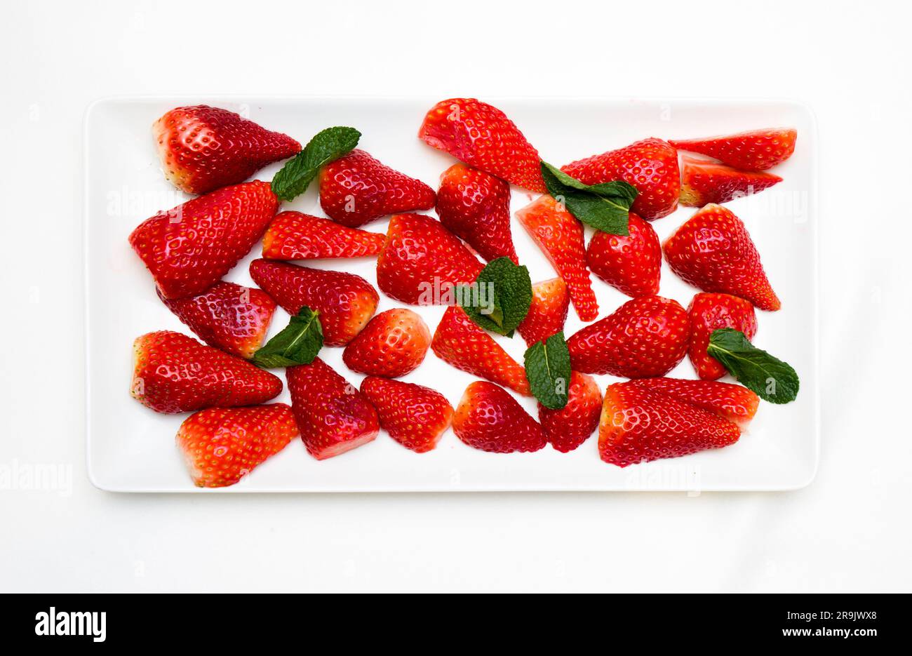 Strawberry in plate on the white table background with strong shadows ...