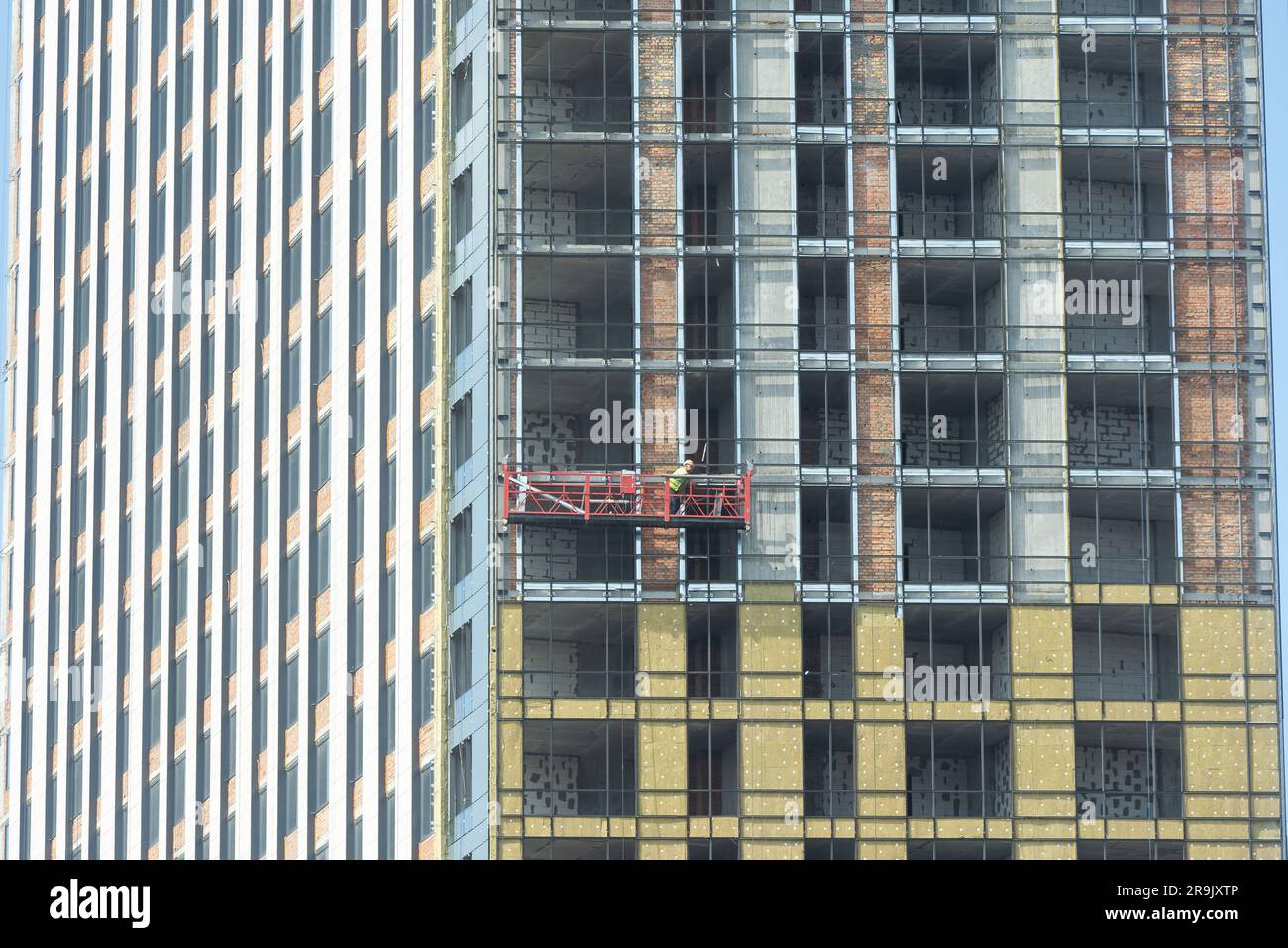 Workers sheathe the outer walls of a brick house with insulation ...