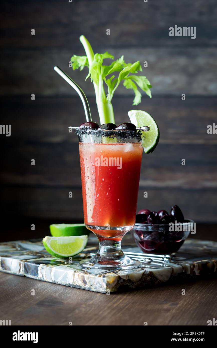 A black salted rim Caesar cocktail garnished with black olives, celery ...