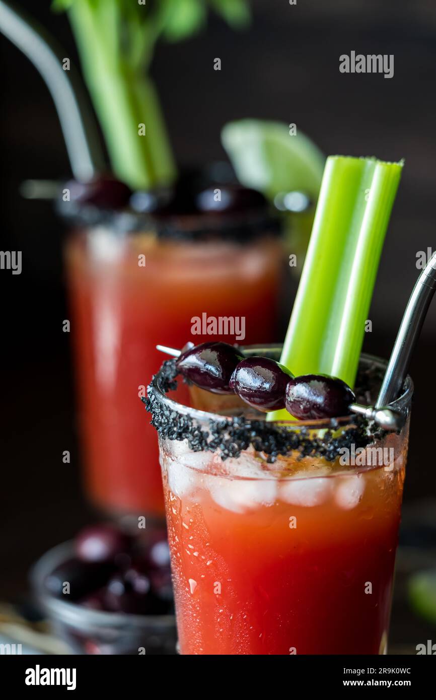 Black rock salted rim Caesar cocktails garnished with black olives and ...