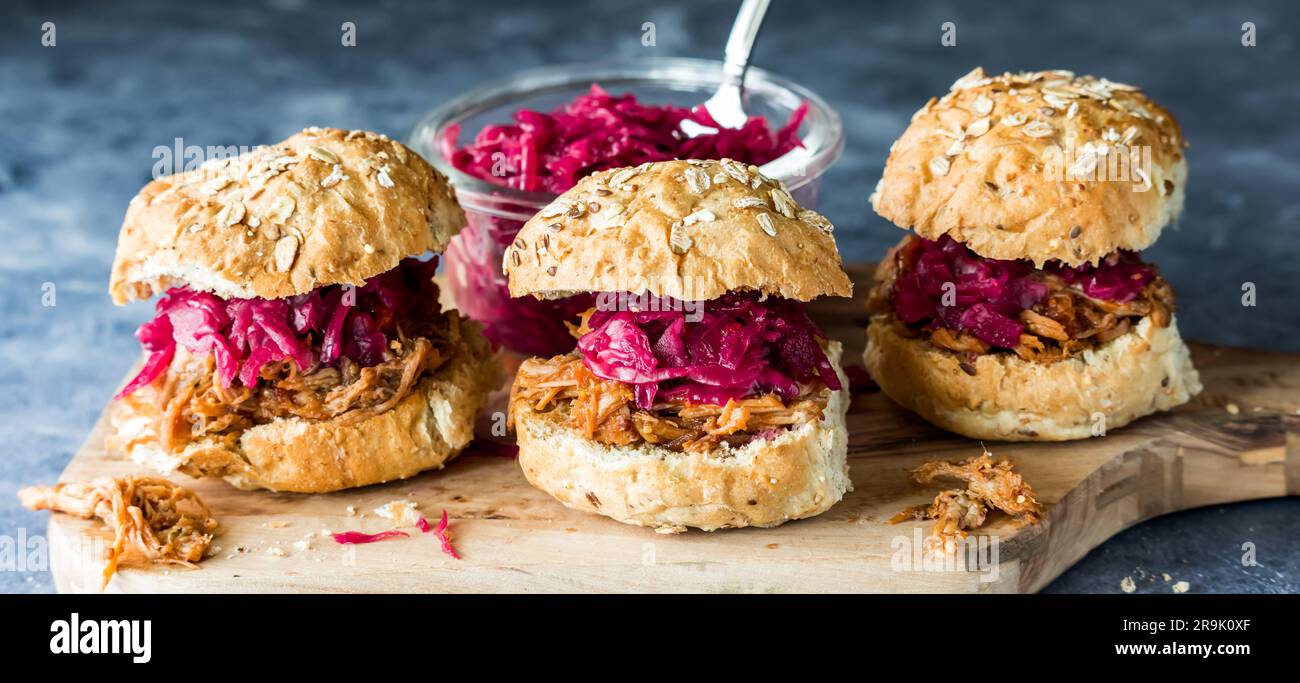 A narrow view of three pulled pork buns topped with pickled beet ...