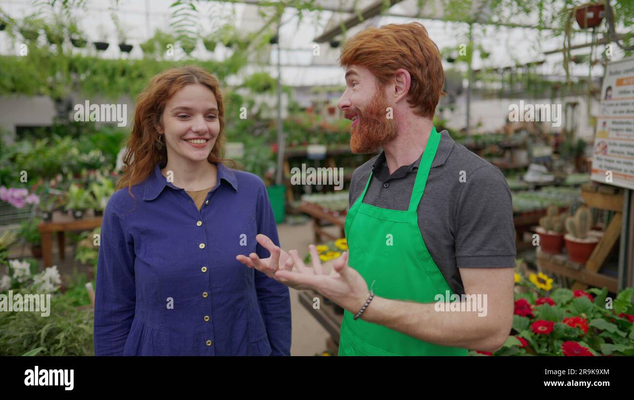 A male florist speaking with female customer inside Flower Shop. Local ...