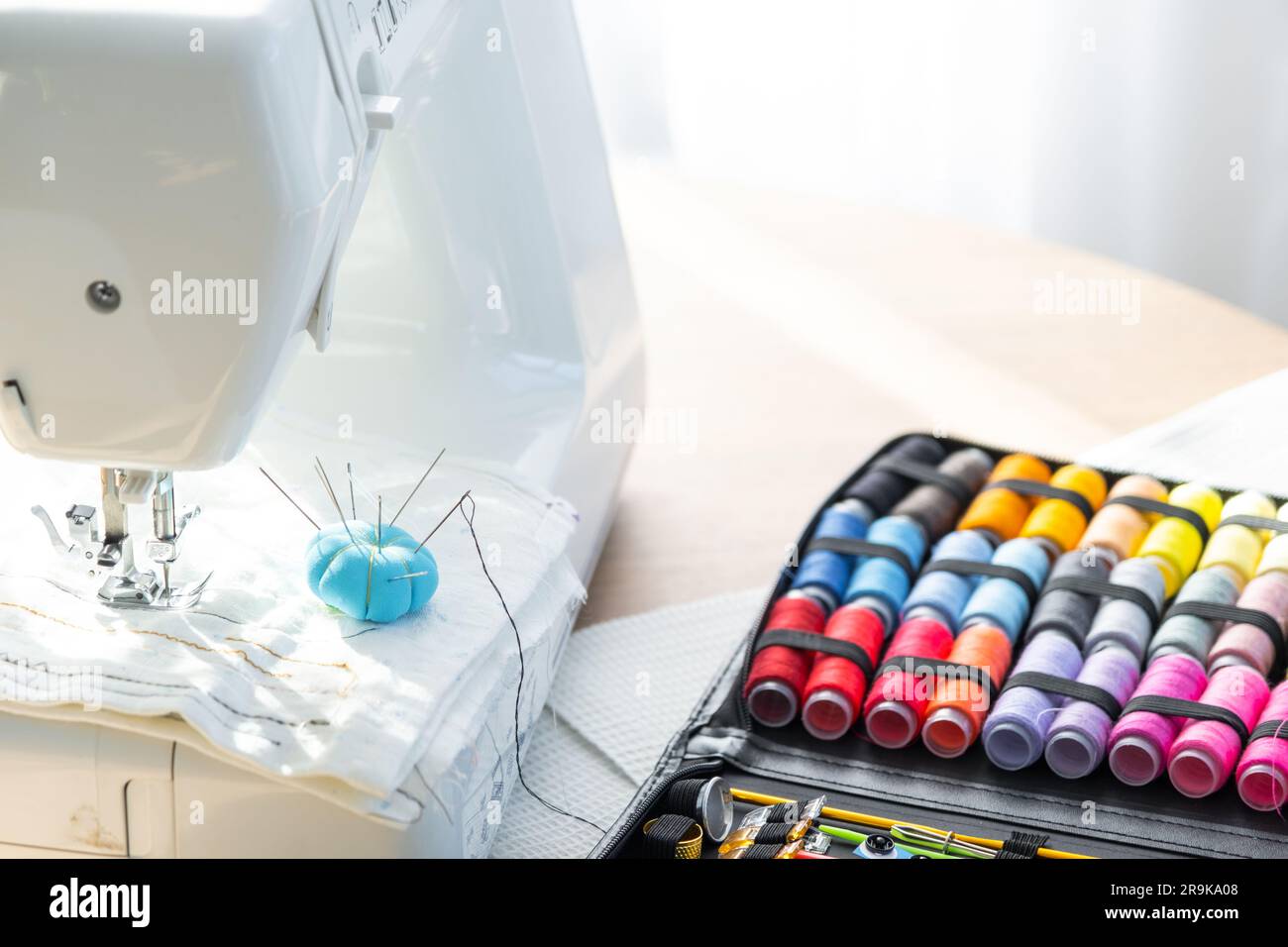Sewing layout with multicolored spools of thread close-up, needles ...