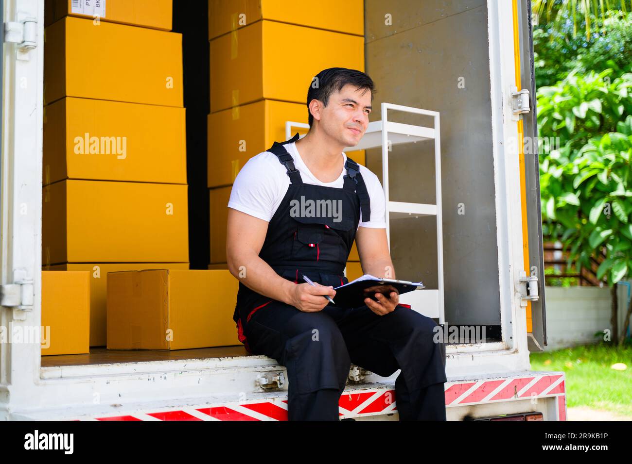 Delivery man sitting on delivery truck working with parcel boxes ...