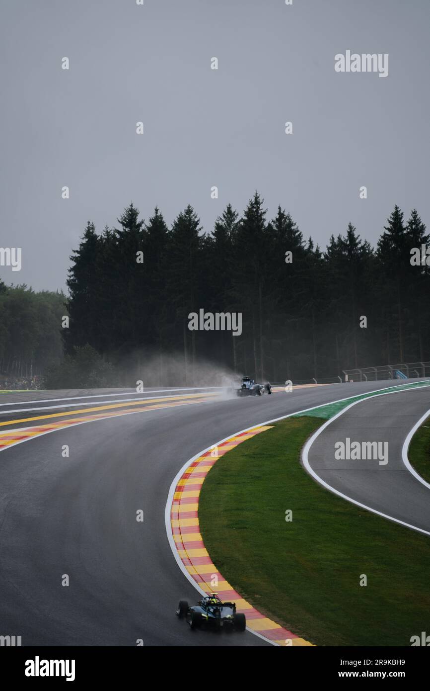 A racing car driving down a race track in front of some trees Stock ...