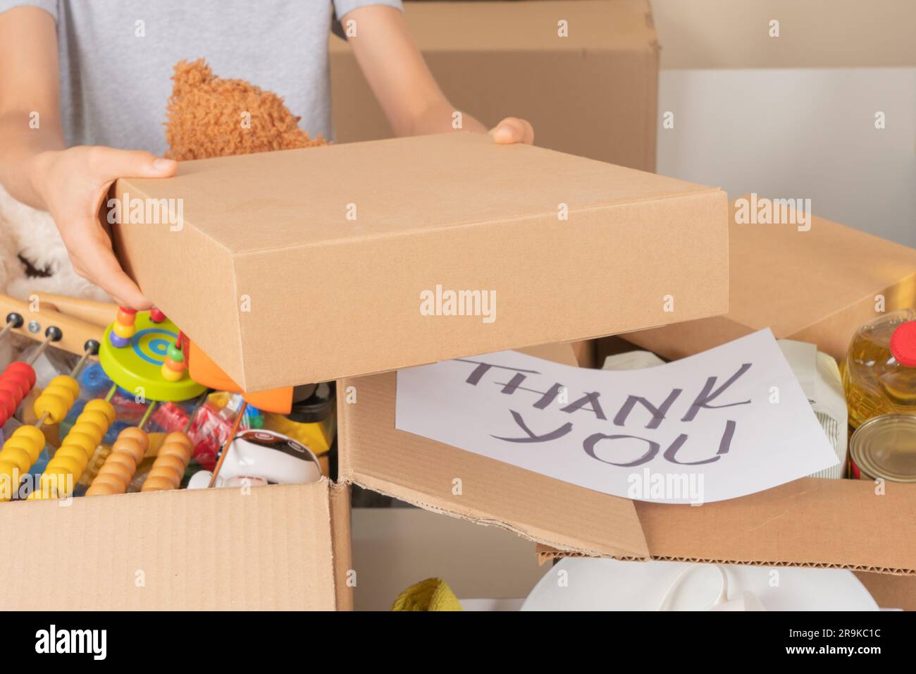 Teenage boy volunteer collecting food into donation box. Donation ...