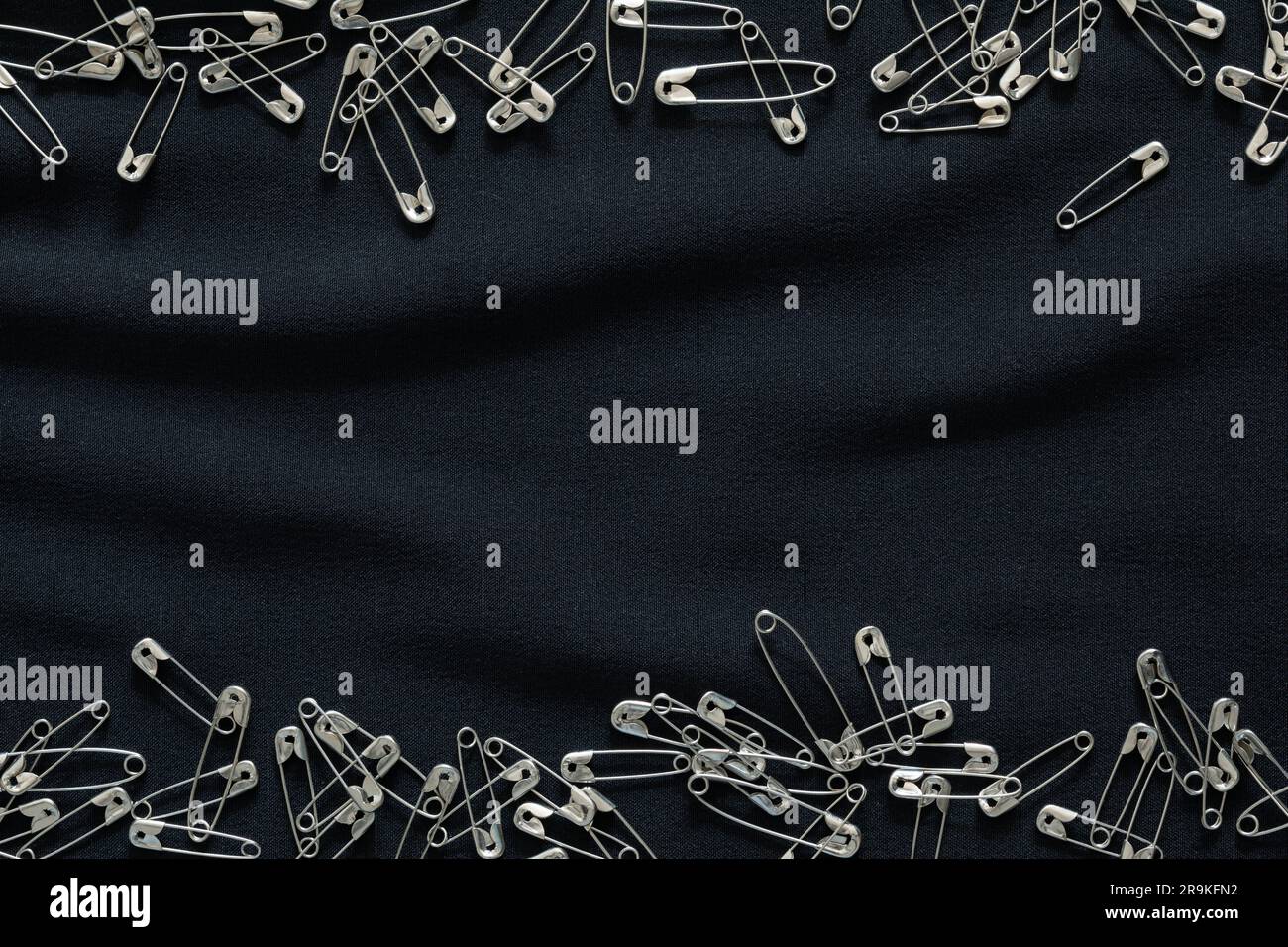 Safety pins on black fabric. Sewing texture background Stock Photo - Alamy