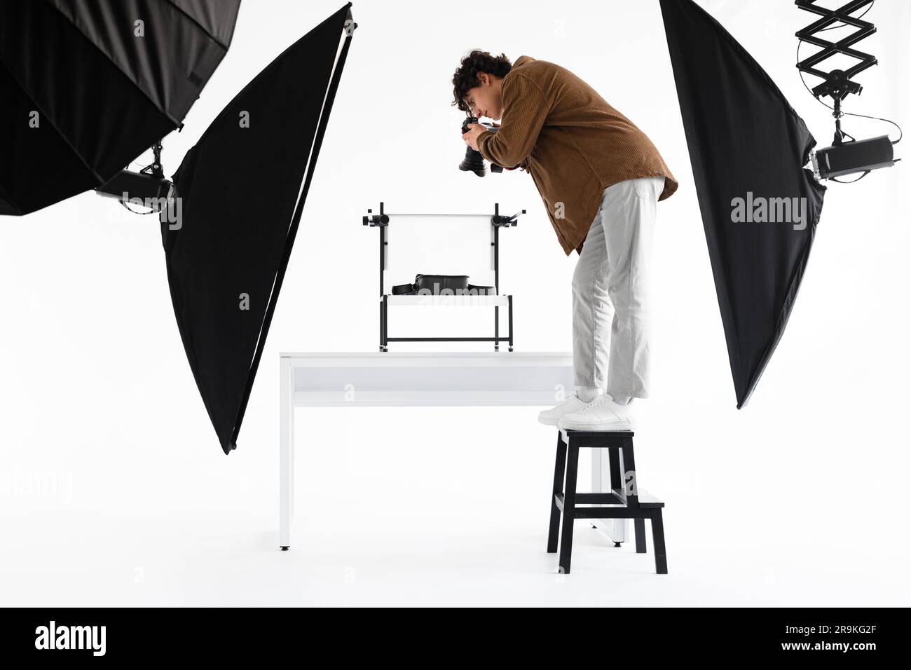 Young man content manager standing on ladder and taking high angle ...