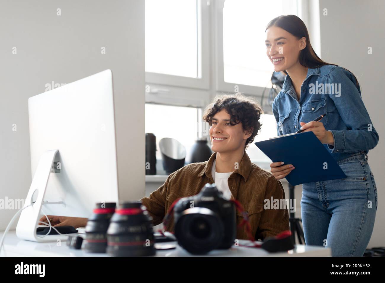 Happy professional team of photographer and assistant looking at ...