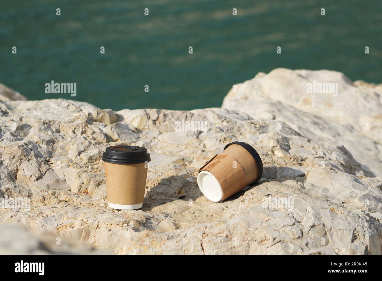 Disposable cardboard cup with plastic lid thrown on floor. Dirty coffee ...